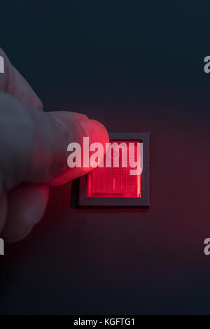Finger hovering over illuminated red electrical switch - potential ...