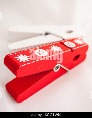 White and red wooden decorated pegs on a white background in studio ...