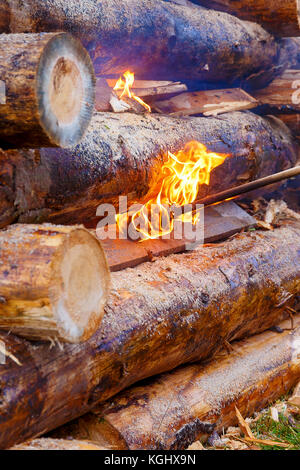 setting big bonfire made of logs on fire with torch Stock Photo - Alamy