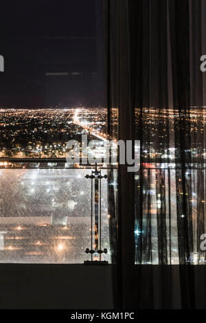Illuminated city seen through curtains over window at night, Las Vegas ...