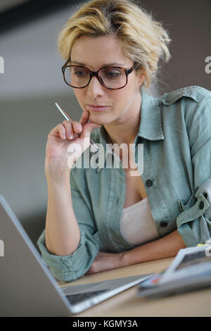 Portrait of blond woman working from home on laptop computer Stock ...