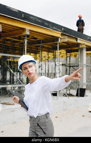 Young beautiful caucasian woman at construction office showing and ...