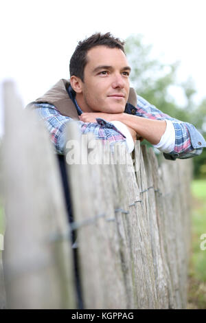 Man in countryside leaning on fence Stock Photo - Alamy