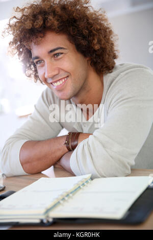 Handsome mixed-race man sitting on ground and calling mechanic as his ...