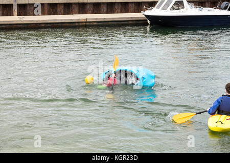 young kayakers training in Falmouth harbour, UK with quayside and boats ...