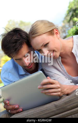 Couple laying on deck chair with electronic tablet Stock Photo - Alamy