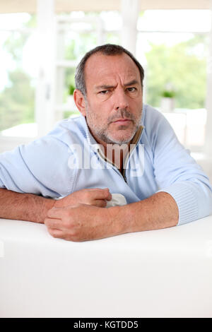 Mature puzzled man with grey beard posing and looking at camera ...