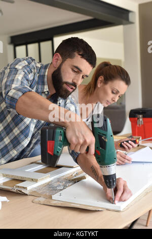 Young man assembling furniture in new house Stock Photo - Alamy