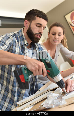 Young man assembling furniture in new house Stock Photo - Alamy