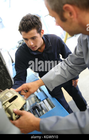 Mechanics teacher with student in car repairshop Stock Photo - Alamy