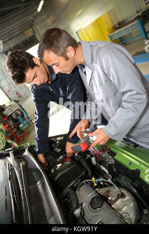 Trainer with student in repairshop checking on battery Stock Photo - Alamy