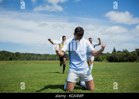 Excited football players celebrating after scoring goal in the ground ...