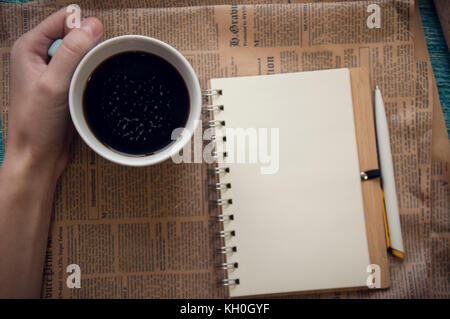 A blank notebook with a pencil and a cofee on a grey wooden background ...
