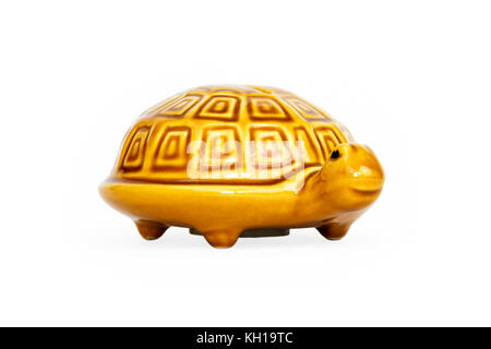 A glazed yellow or orange ceramic tortoise money box, against a white ...