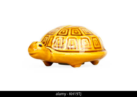 A glazed yellow or orange ceramic tortoise money box, against a white ...