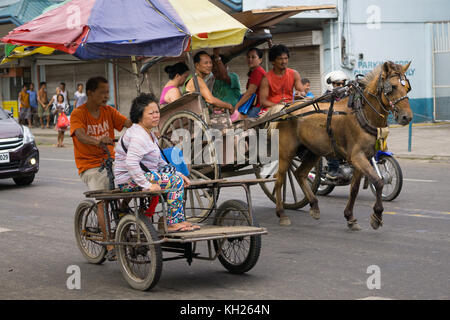 A horse drawn carriage known as a Kalesa being driven in downtown Cebu ...