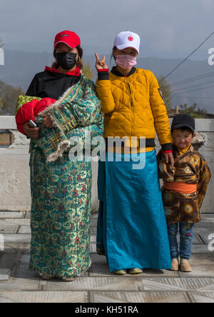 Three Tibetan women pilgrims in traditional dress take a break while ...