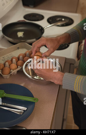 Caucasian man cracking egg in a bowl in the kitchen for cooking Stock ...