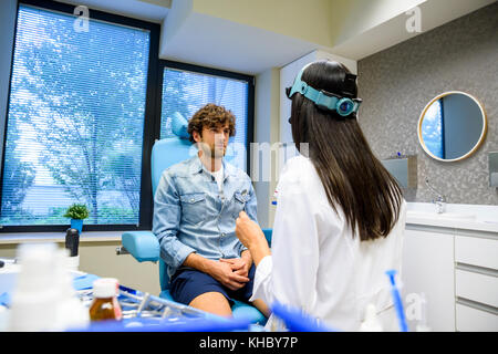 A female Ear-Nose-Throat aka ENT specialist doctor diagnosing a young ...