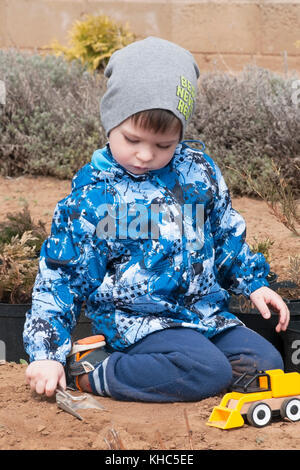 small child in garden digs beds for planting plants. Gardeners hands ...