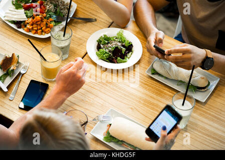 friends with smartphones eating at restaurant Stock Photo - Alamy