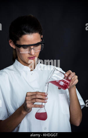 Assistant pouring liquid into flask Stock Photo - Alamy