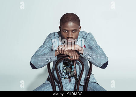 Man sitting on chair backwards leaning arms on back of chair, white ...