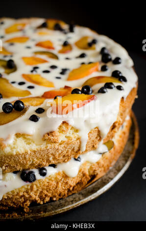 slices of biscuit plum cake on a white wooden board and fresh fruits ...