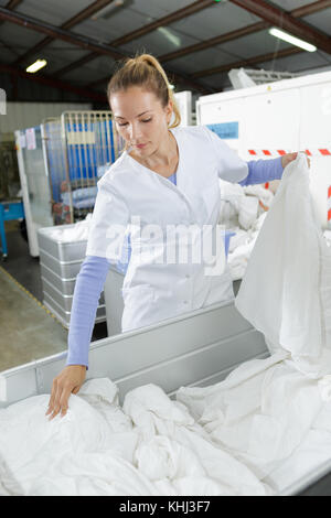 laundry worker puts ironed textile in ironing machine Stock Photo - Alamy