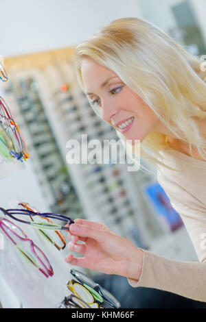 Woman comparing two pairs of eyesight glasses isolated on white ...