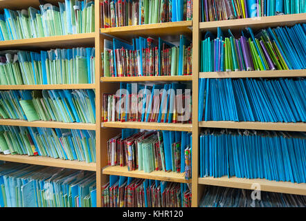 A stack of patient medical records in folders with color-coded and ...