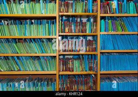 A stack of patient medical records in folders with color-coded and ...
