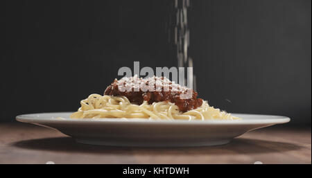 sprinkle grated aged parmesan cheese over spaghetti bolognese Stock ...