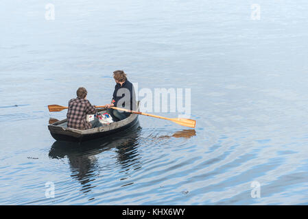 Two men in a rowing boat who pass the lines to the ships entering the ...