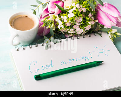 Rose flowers and good morning wish in notepad. Close up. White wooden ...