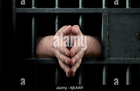 A closeup of a dimly lit prison holding cell door with arms reaching ...