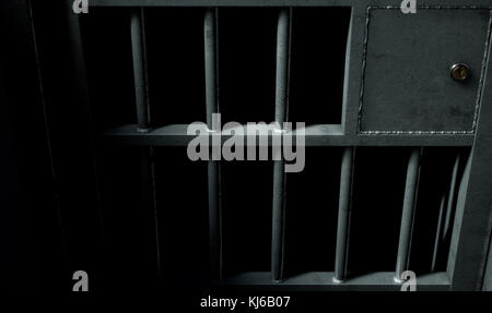 A closeup of a dimly lit prison holding cell door with arms reaching ...