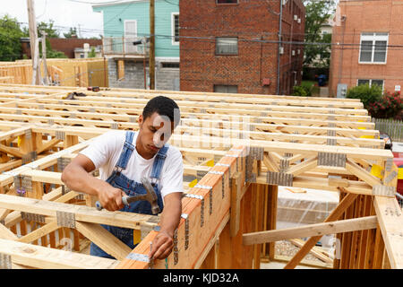 Black man hammering nail at construction site Stock Photo - Alamy
