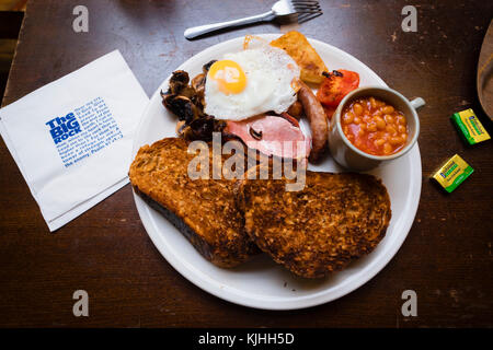 Plate with full Welsh fried cooked breakfast of egg, sausage, bacon ...
