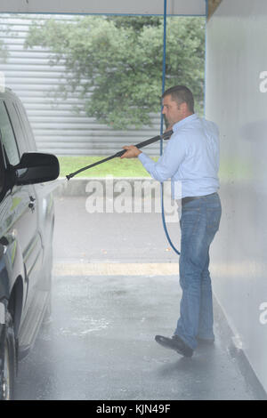 A man spraying pressure washer for car wash in car care shop. Focus on ...
