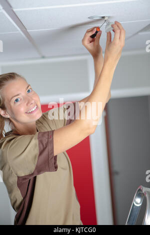 woman on ladder fitting light bulb in new house Stock Photo - Alamy