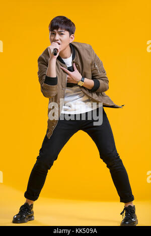 Cheerful young Chinese man singing with microphone Stock Photo - Alamy