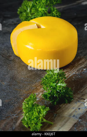 Round gouda cheese with parsley. Dark background Stock Photo - Alamy