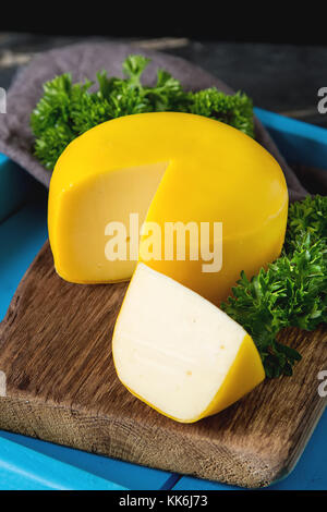 Round gouda cheese with parsley. Dark background Stock Photo - Alamy