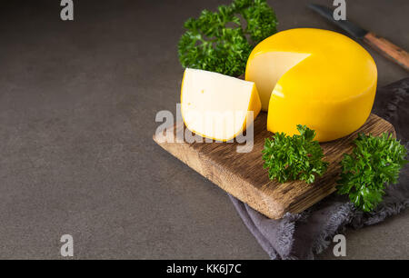 Round gouda cheese with parsley. Dark background Stock Photo - Alamy