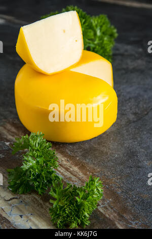 Round gouda cheese with parsley. Dark background Stock Photo - Alamy
