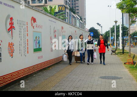 Shenzhen, China: street propaganda walls, painted walls, tourists pass ...