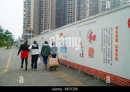 Shenzhen, China: street propaganda walls, painted walls, tourists pass ...