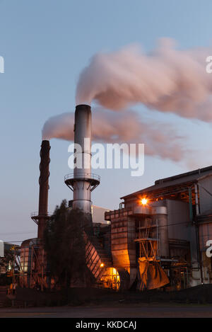 Australia. Queensland. Bundaberg sugar mill, smoking chimney stacks ...