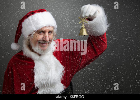 Jingle bells. Santa Claus holding metal bell in his hand and against ...